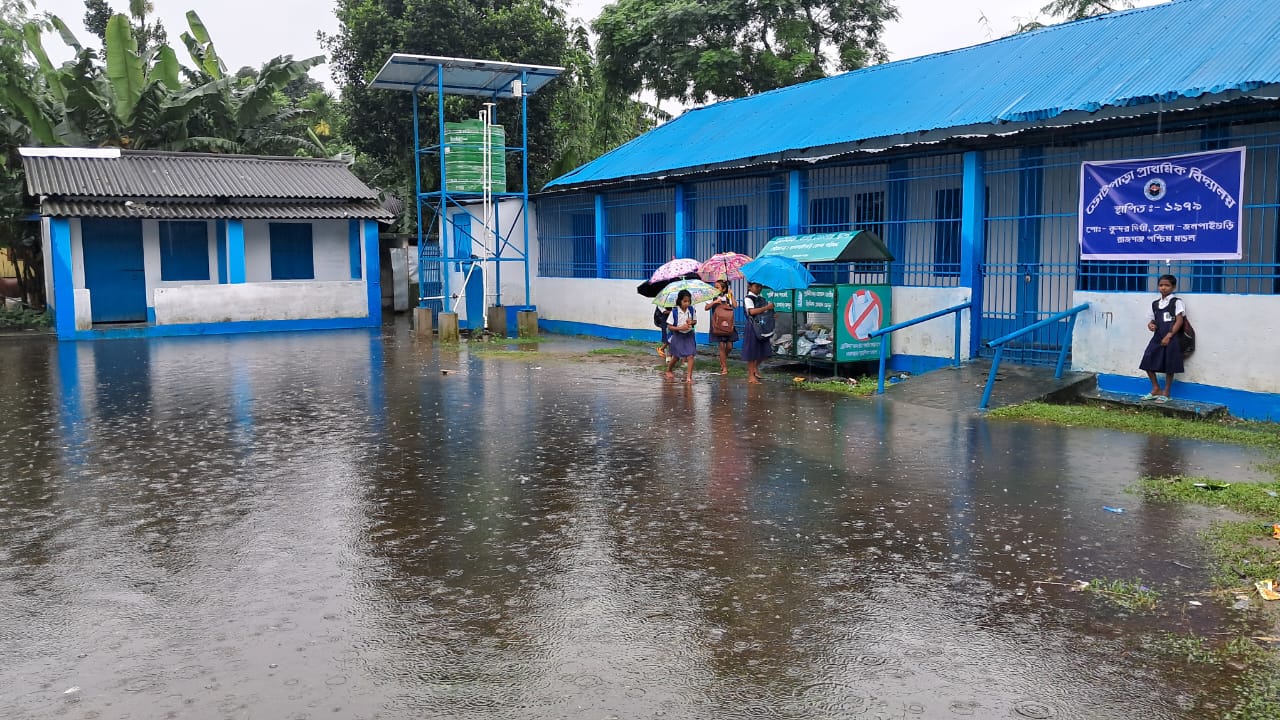 Students travel across knee-deep water on the school grounds in Rajganj ...